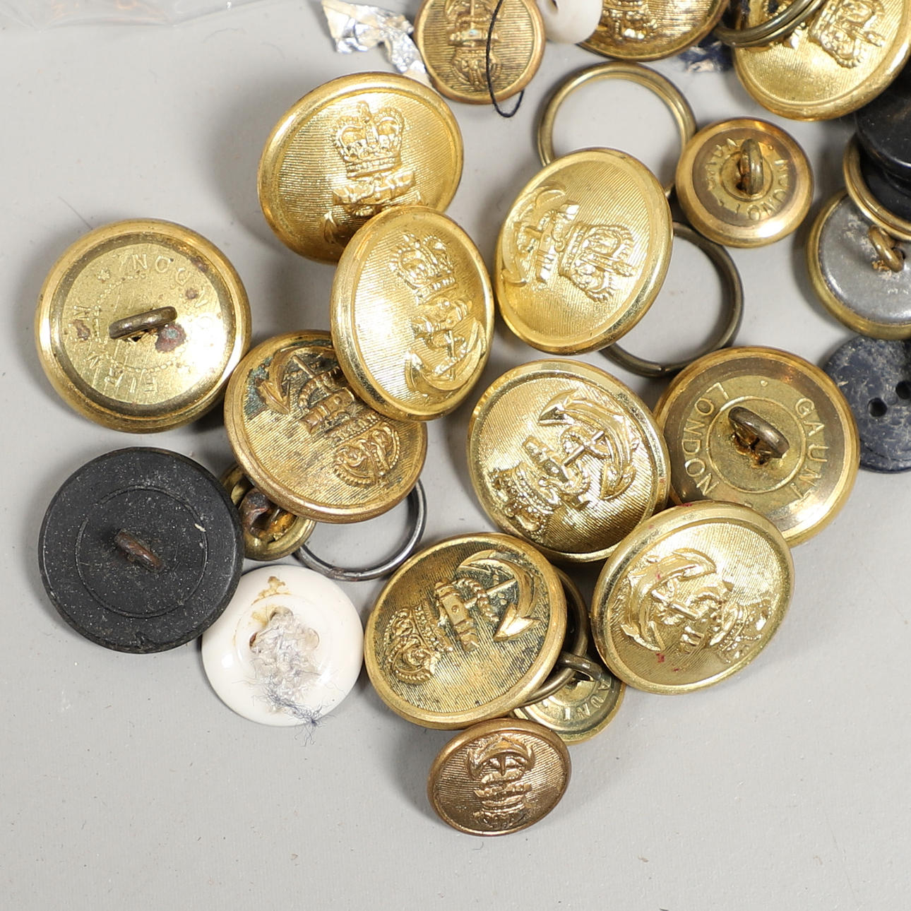 A COLLECTION OF ROYAL NAVY BUTTONS AND INSIGNIA AND A LARGE SHELL ...