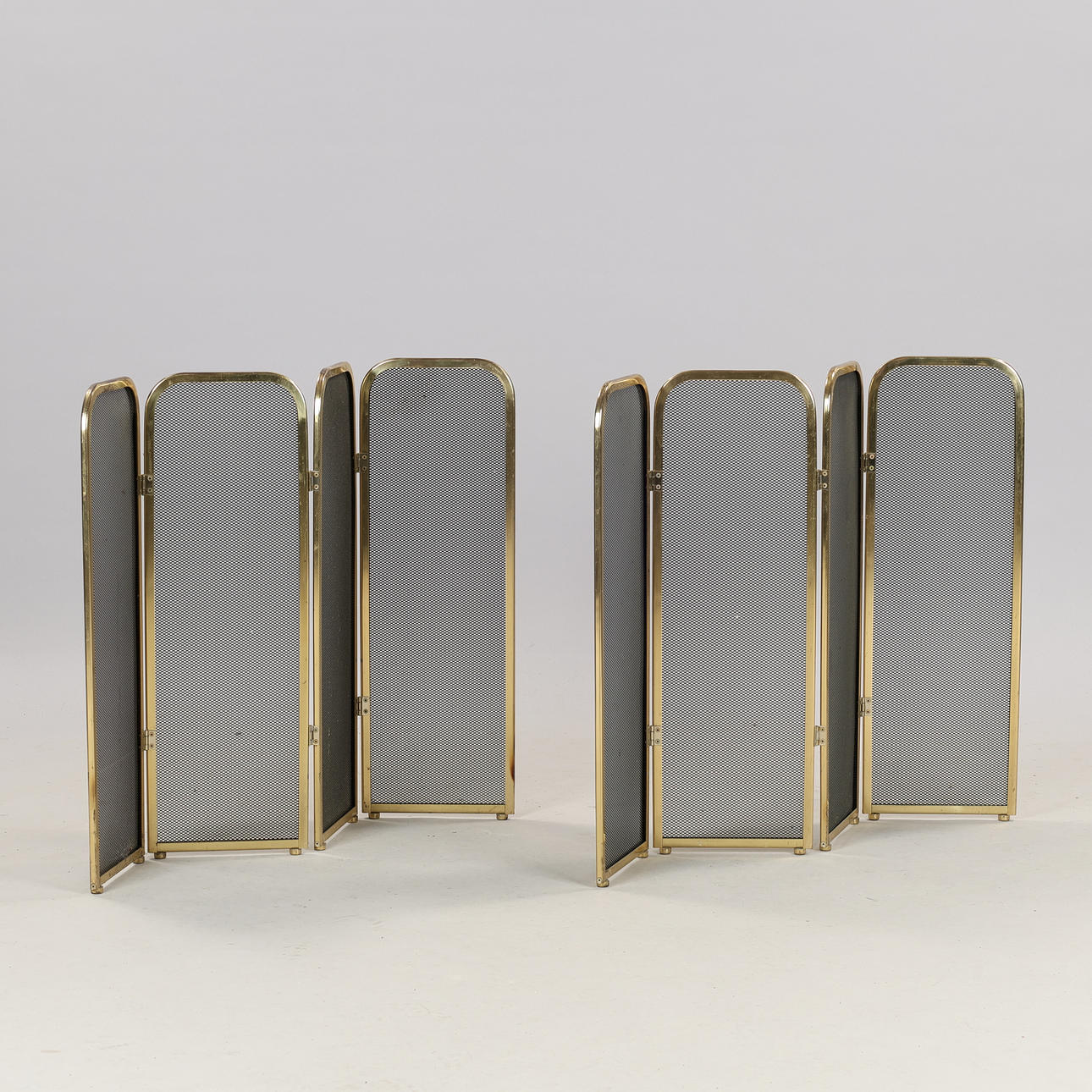 A pair of folding fireplace screens made of brass and black wire mesh ...