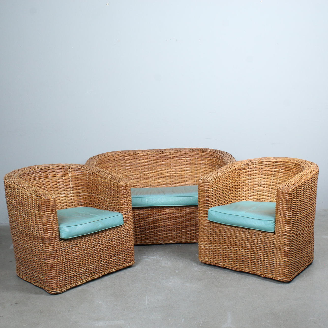 Par loungestolar och en soffa i Michael Taylor-stil av flätad rotting ...