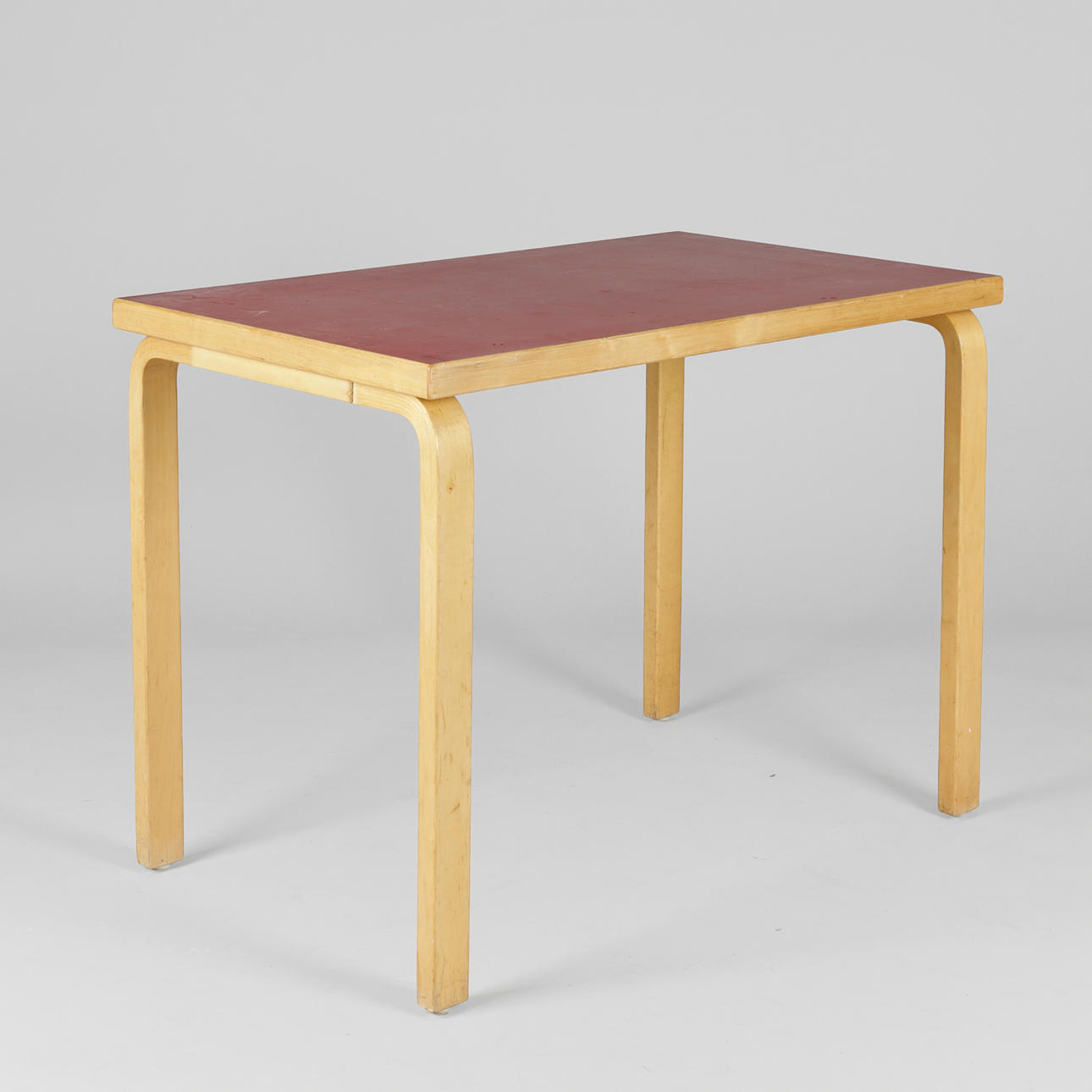 ALVAR AALTO. Rectangular table in lacquered birch, top with red ...
