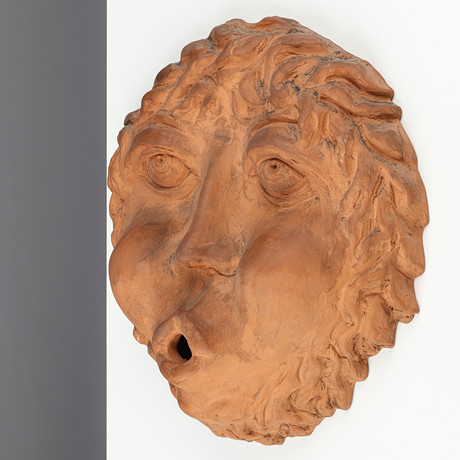 WALL-HUNG MASK of red clay depicting face with a blowing expression ...